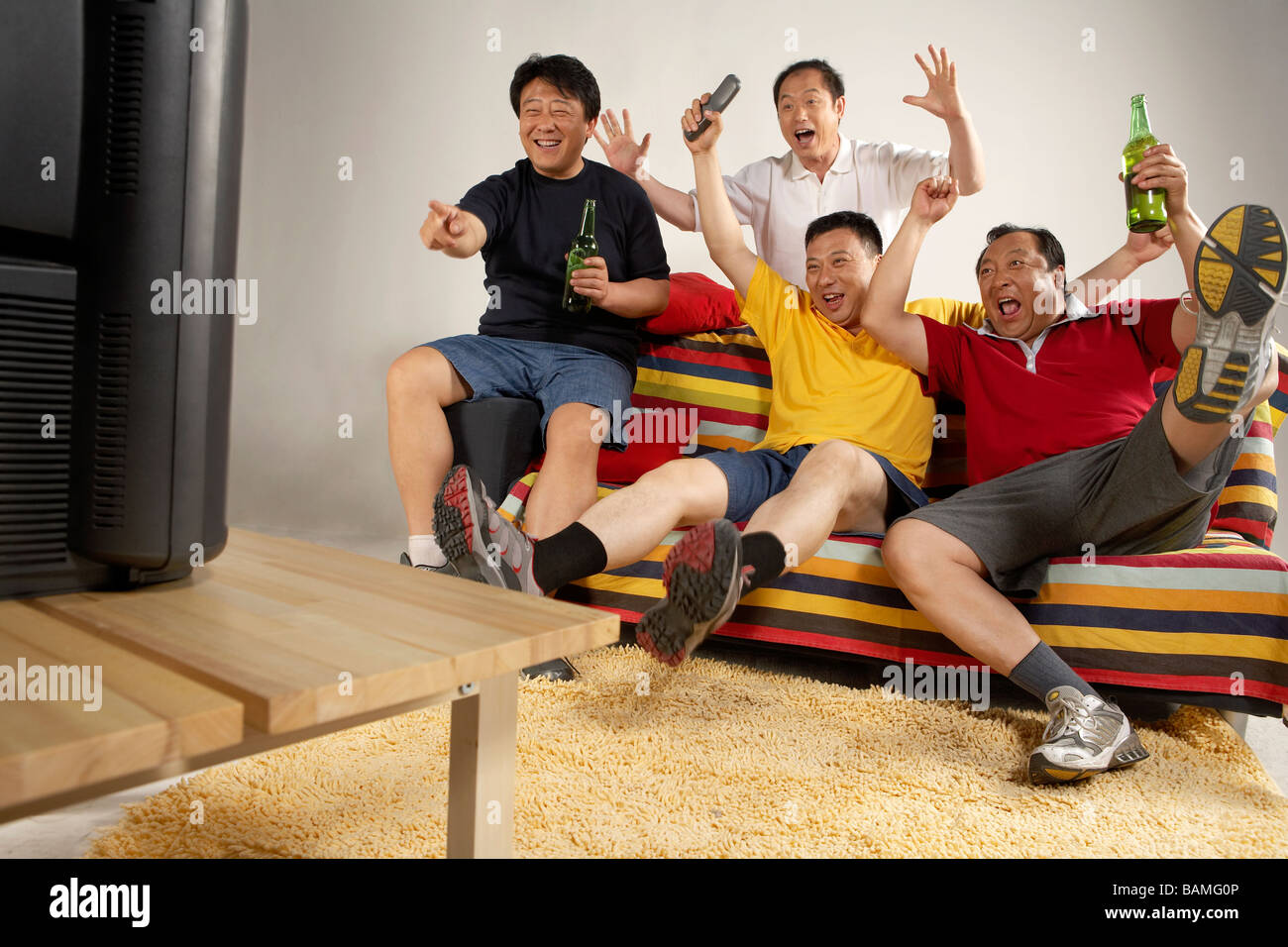 Fans Sitting On A Couch Cheering At The Television Stock Photo - Alamy