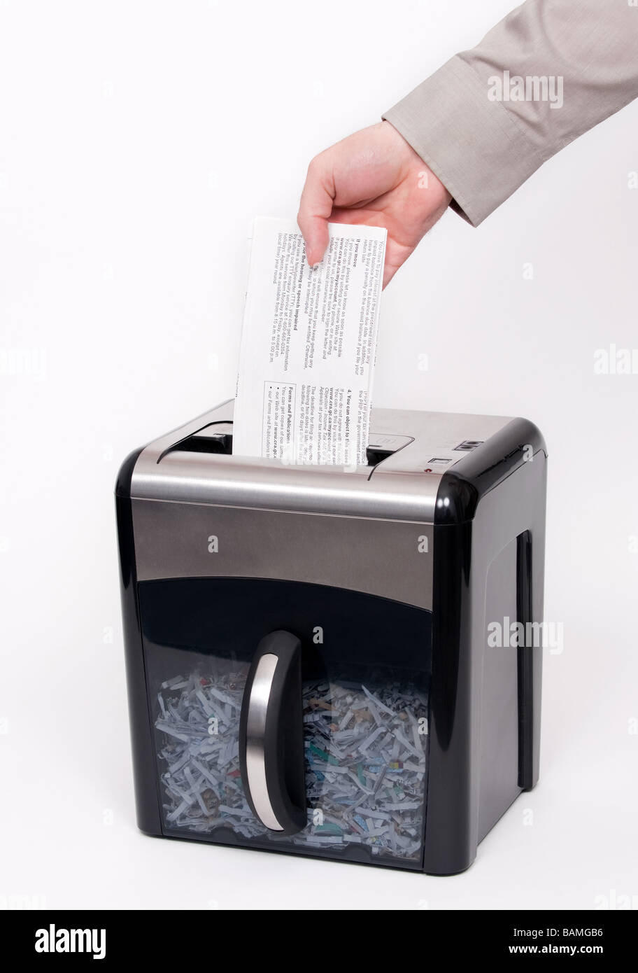 A man putting confidential documents into a paper shredder Stock Photo ...