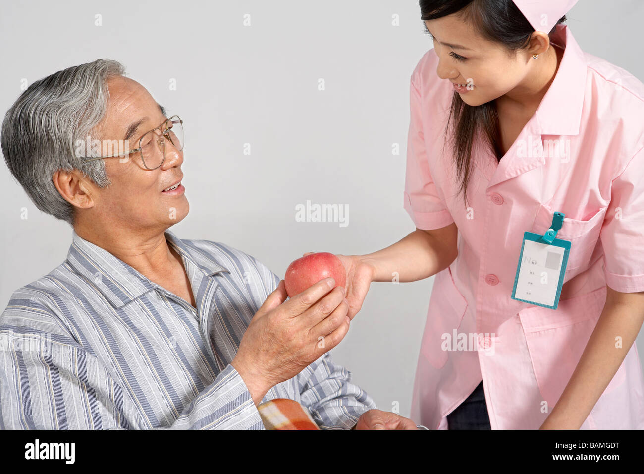 Nurse Giving An Apple To Man Stock Photo - Alamy
