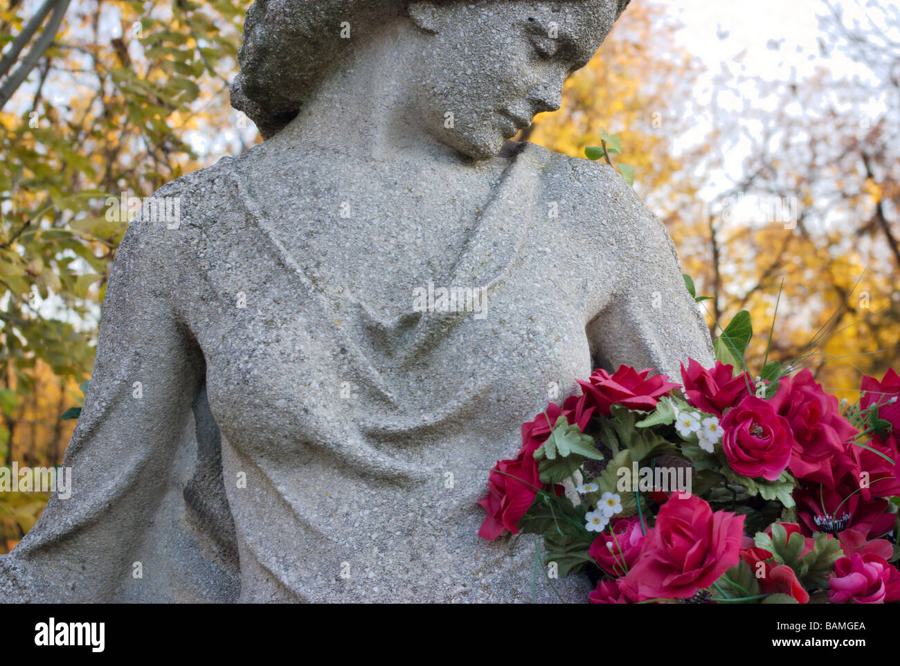 Statue of woman in cemetery with red flowers Stock Photo - Alamy
