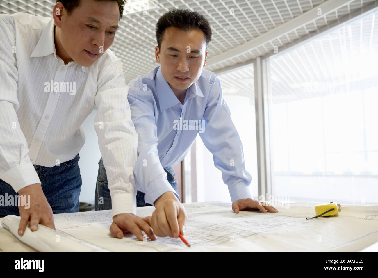 Architects Looking At Building Plans Together Stock Photo - Alamy