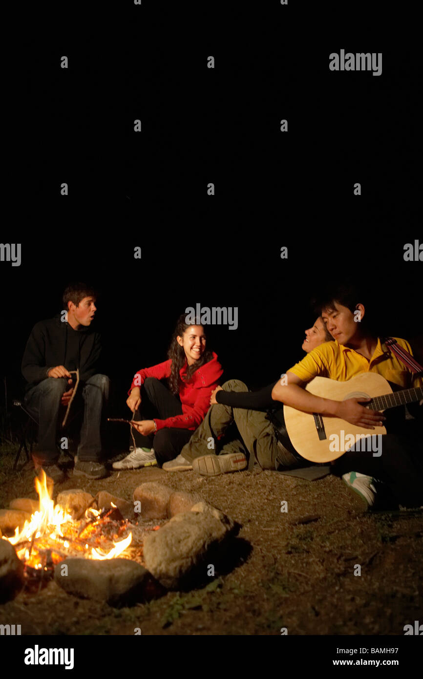 Young People Sitting Around Campfire Stock Photo - Alamy