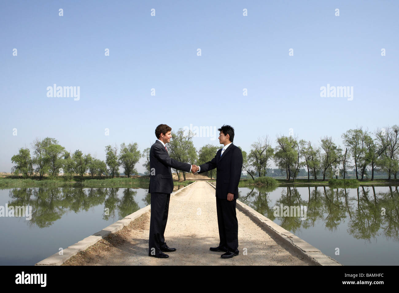Businessmen Standing Next To A Lake On A Bridge Stock Photo - Alamy