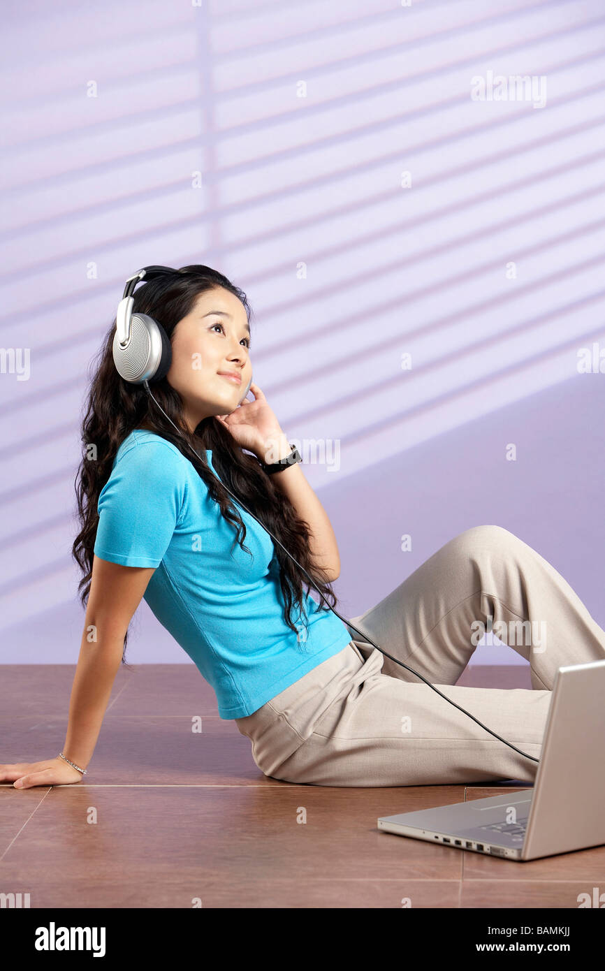 Woman Sitting On Floor With Computer Wearing Headphones Stock Photo - Alamy