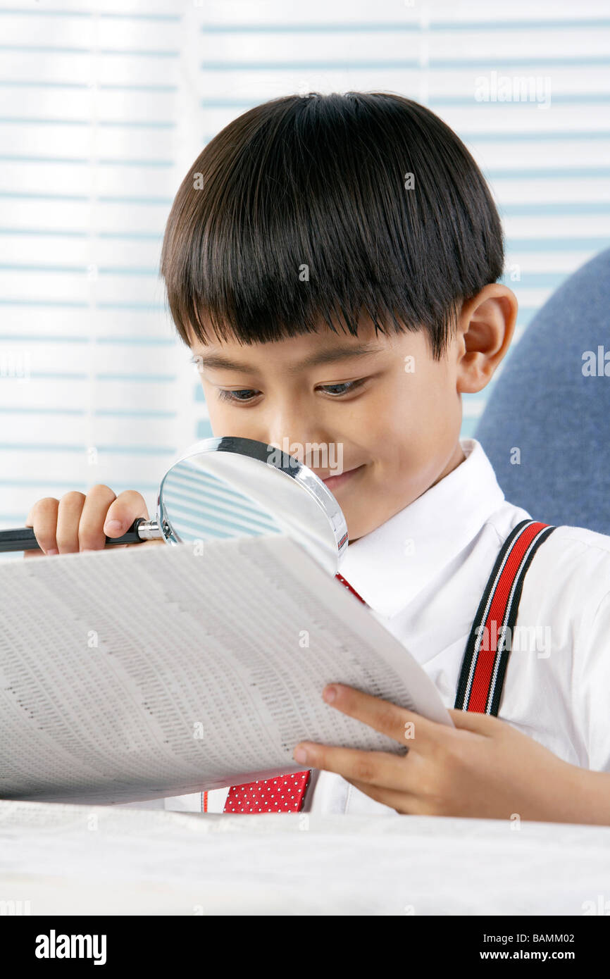 Young Boy Reading Paper With A Magnifying Glass Stock Photo - Alamy