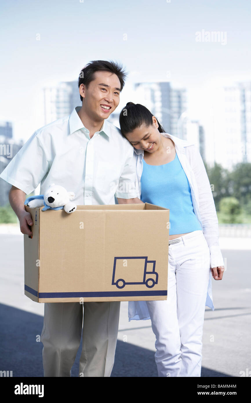 Man Carrying A Box Smiling While Woman Leans On Him Stock Photo - Alamy