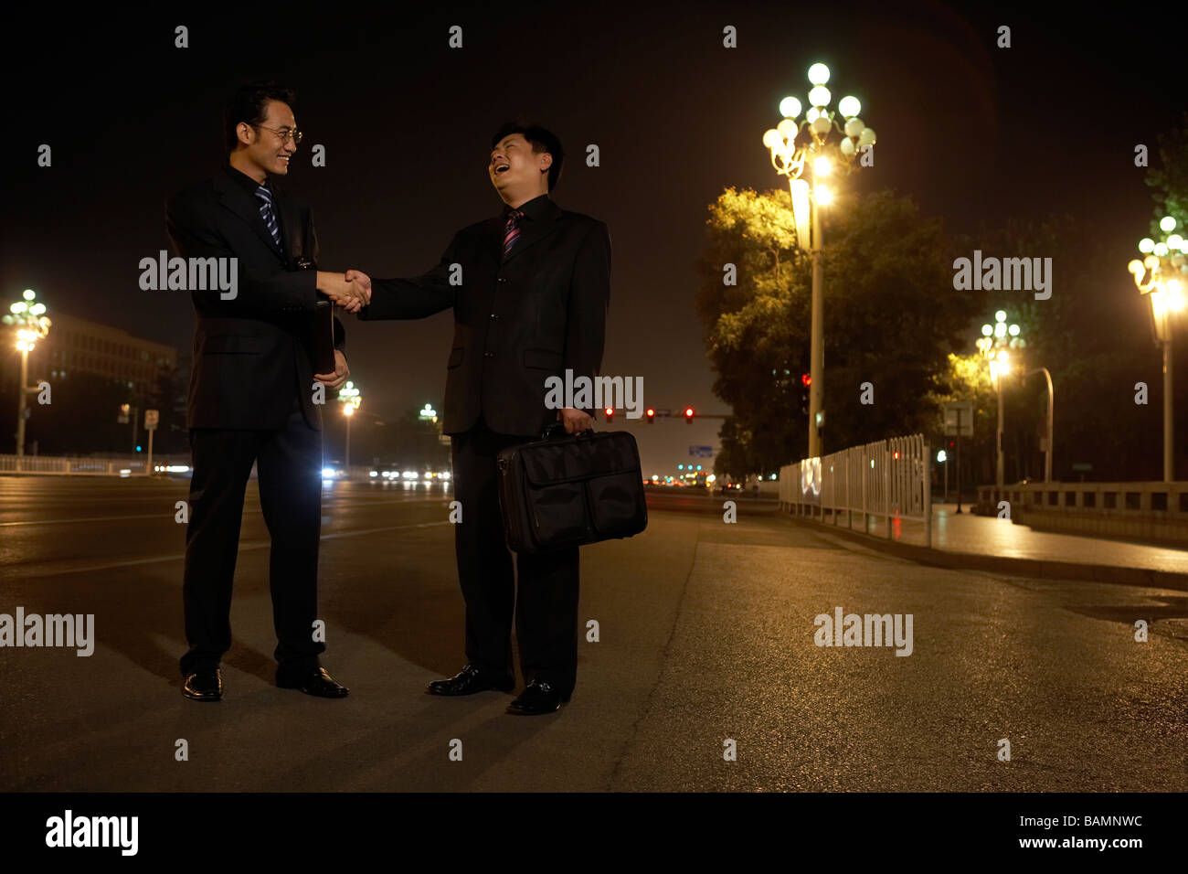 Two Businessmen Shaking Hands Outside At Night Stock Photo - Alamy