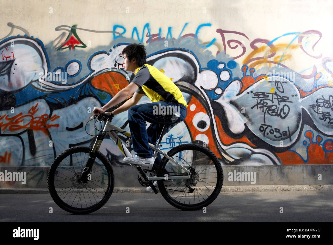 Teenage Boy Riding A Bike Past Graffiti Stock Photo - Alamy