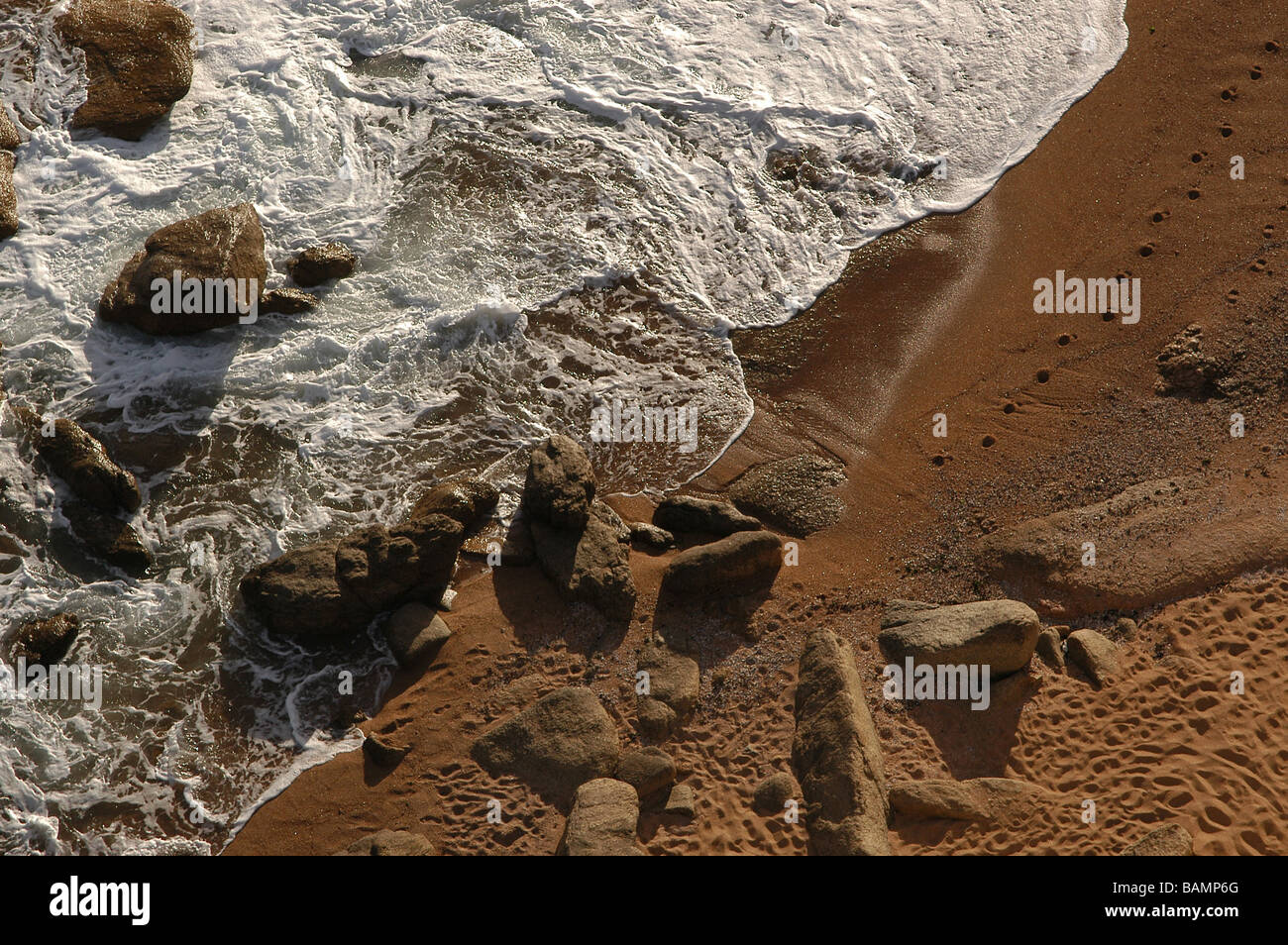 zenithal view from a lighthouse, sand and rocks and water footprints ...