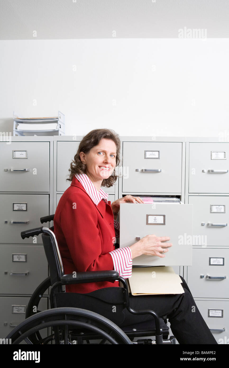 Woman in a wheelchair opening drawer on file cabinet Stock Photo - Alamy