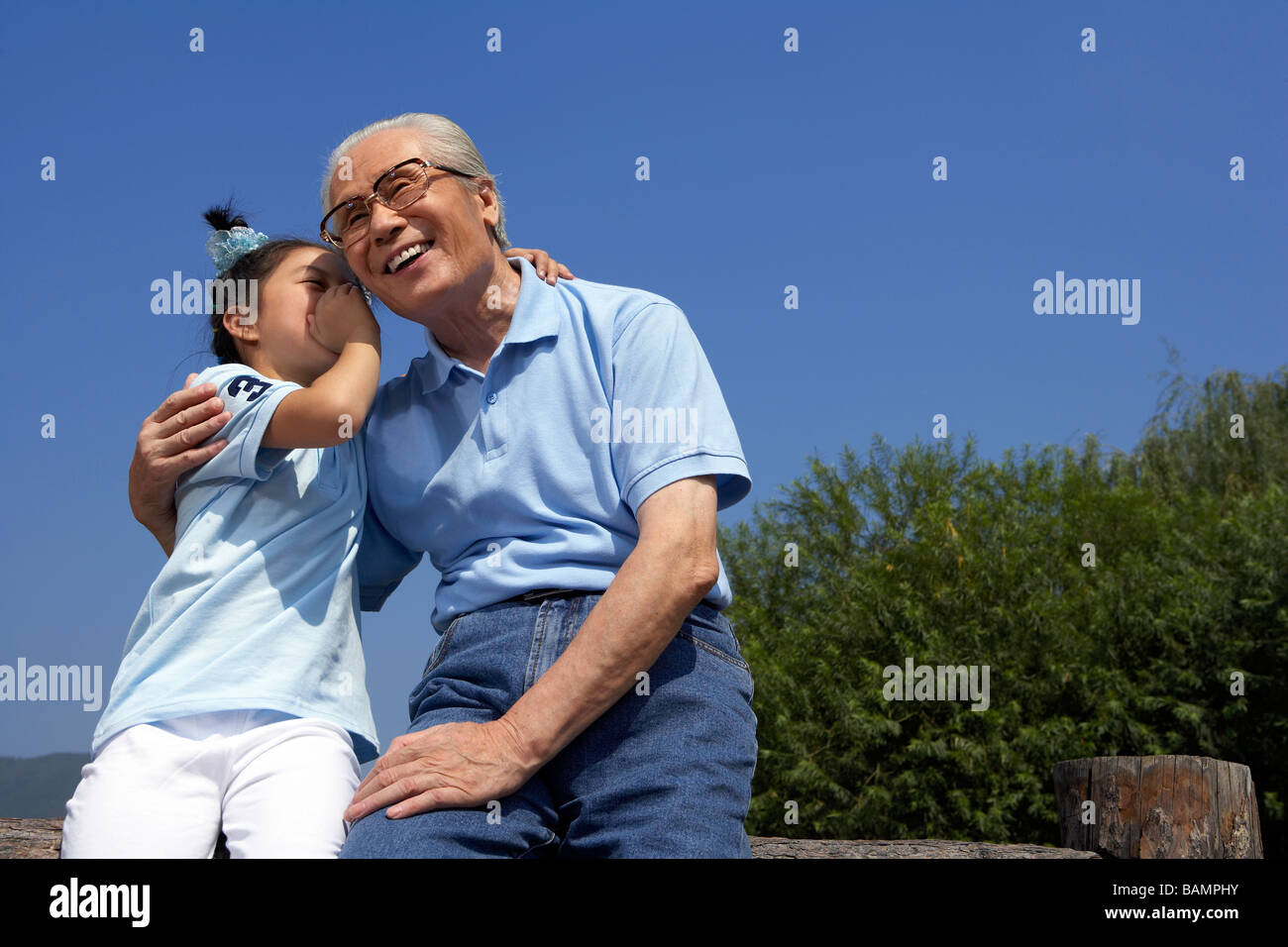 Granddaughter Whispering In Grandfather's Ear Stock Photo - Alamy