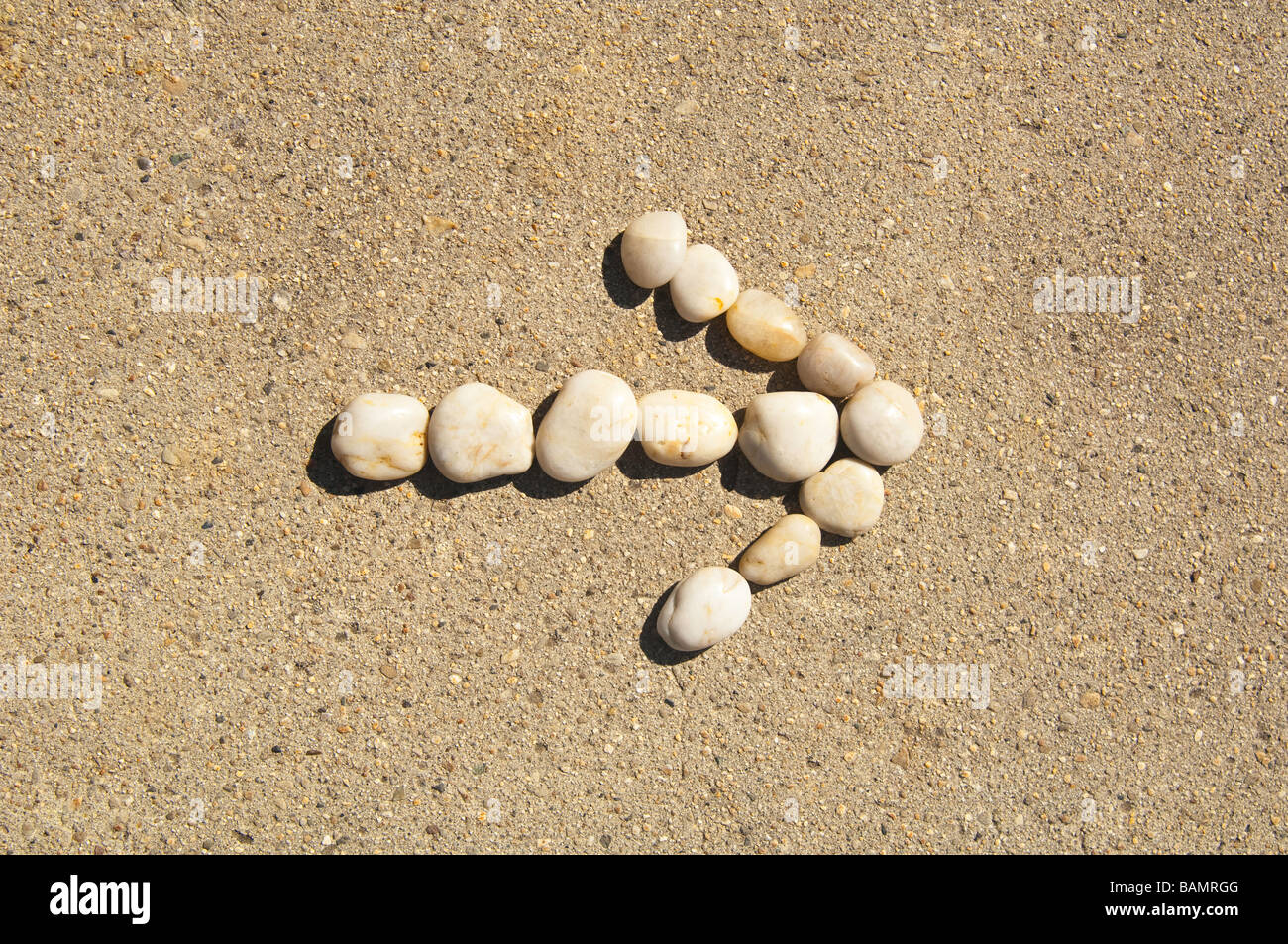 Arrow formed of small white stones Stock Photo - Alamy