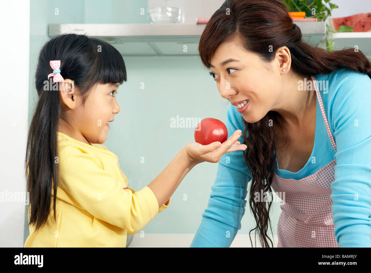 Girl Giving Mother A Tomato Stock Photo - Alamy