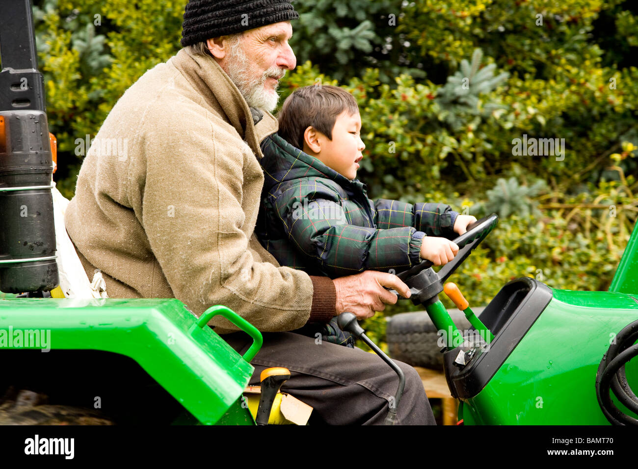 Boy driving a tractor with assistance of male adult Stock Photo - Alamy