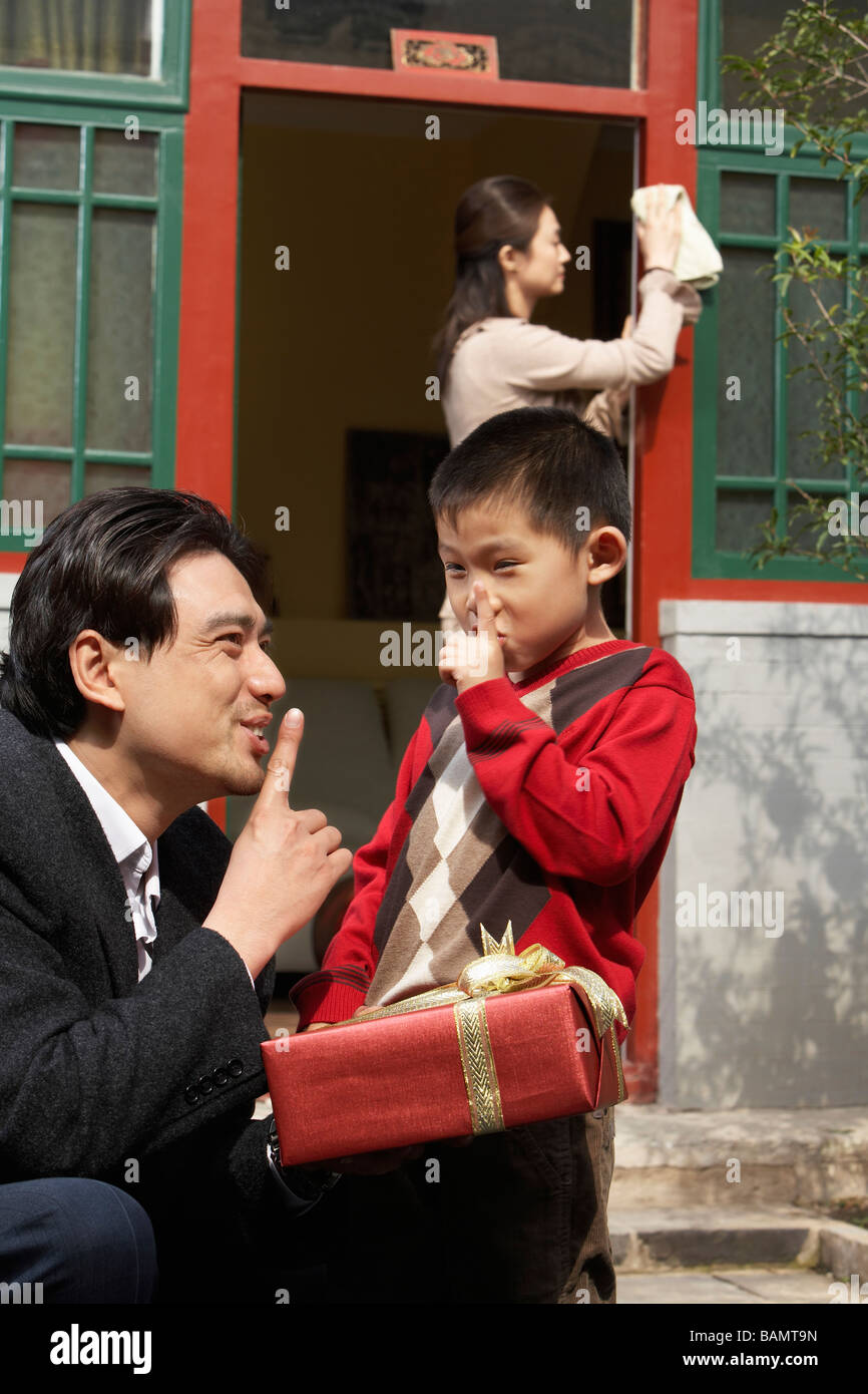 Father Giving Son A Secret Gift While Mother Cleans Stock Photo - Alamy