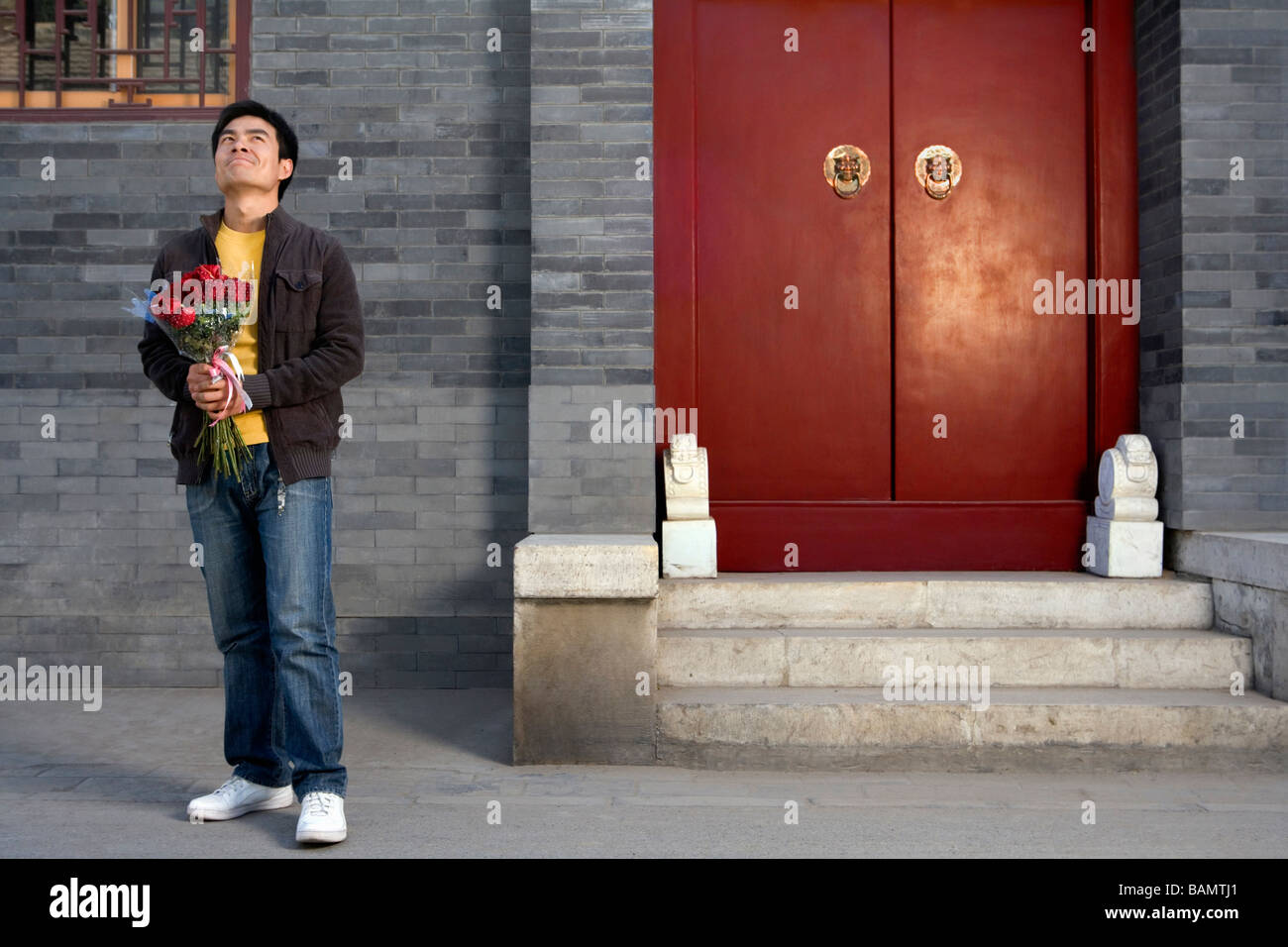 Young Man Waiting Outside Building Entrance Holding A Bunch Of Roses ...