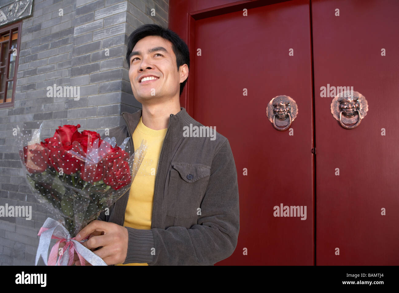 Young Man Waiting Outside Building Entrance Holding A Bunch Of Roses ...