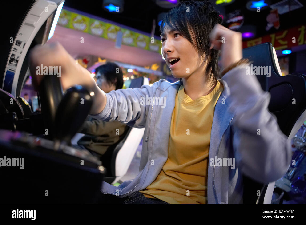 Teenagers Playing Racing Games At Arcade Stock Photo - Alamy