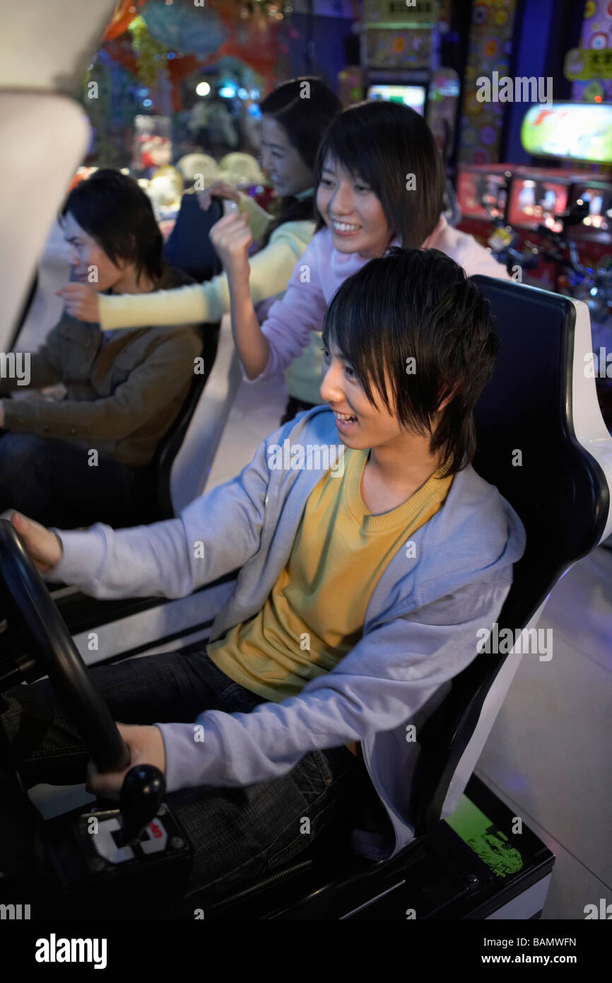 Teenagers Playing Racing Games At Arcade Stock Photo - Alamy