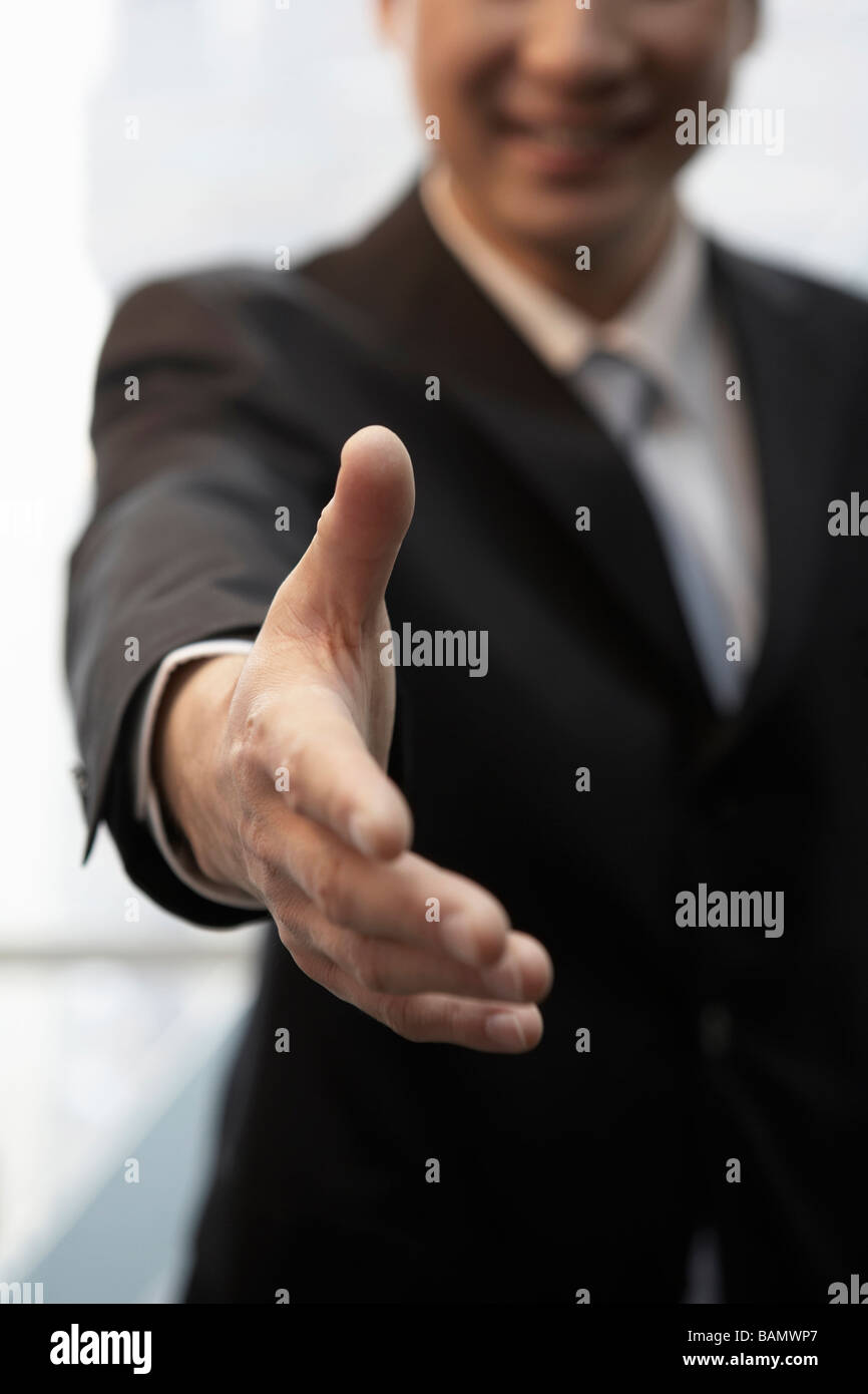 Businessman In Office Reaching Out To Shake Hands Stock Photo - Alamy