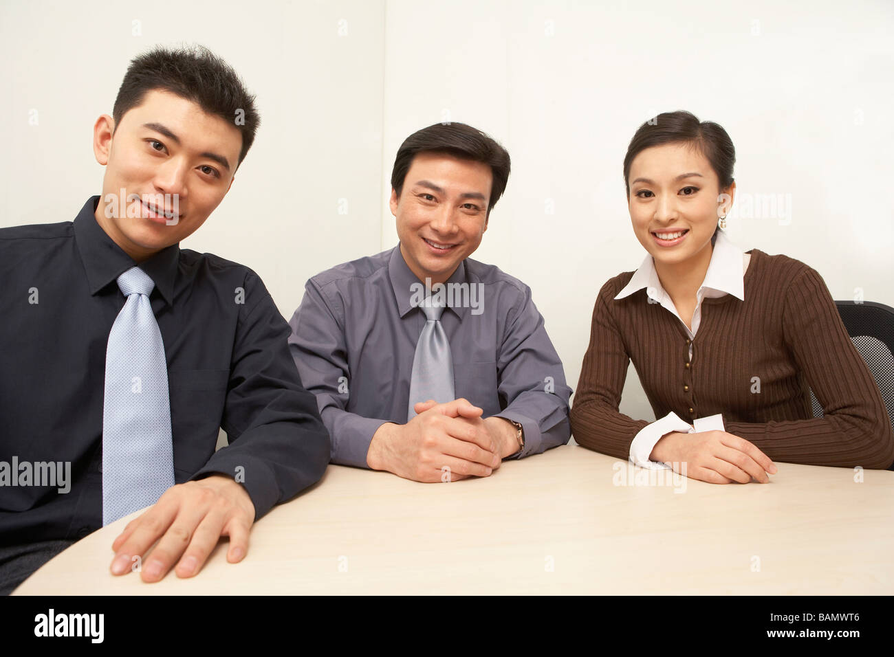 Businesspeople Sitting Around A Conference Table, Smiling Stock Photo ...