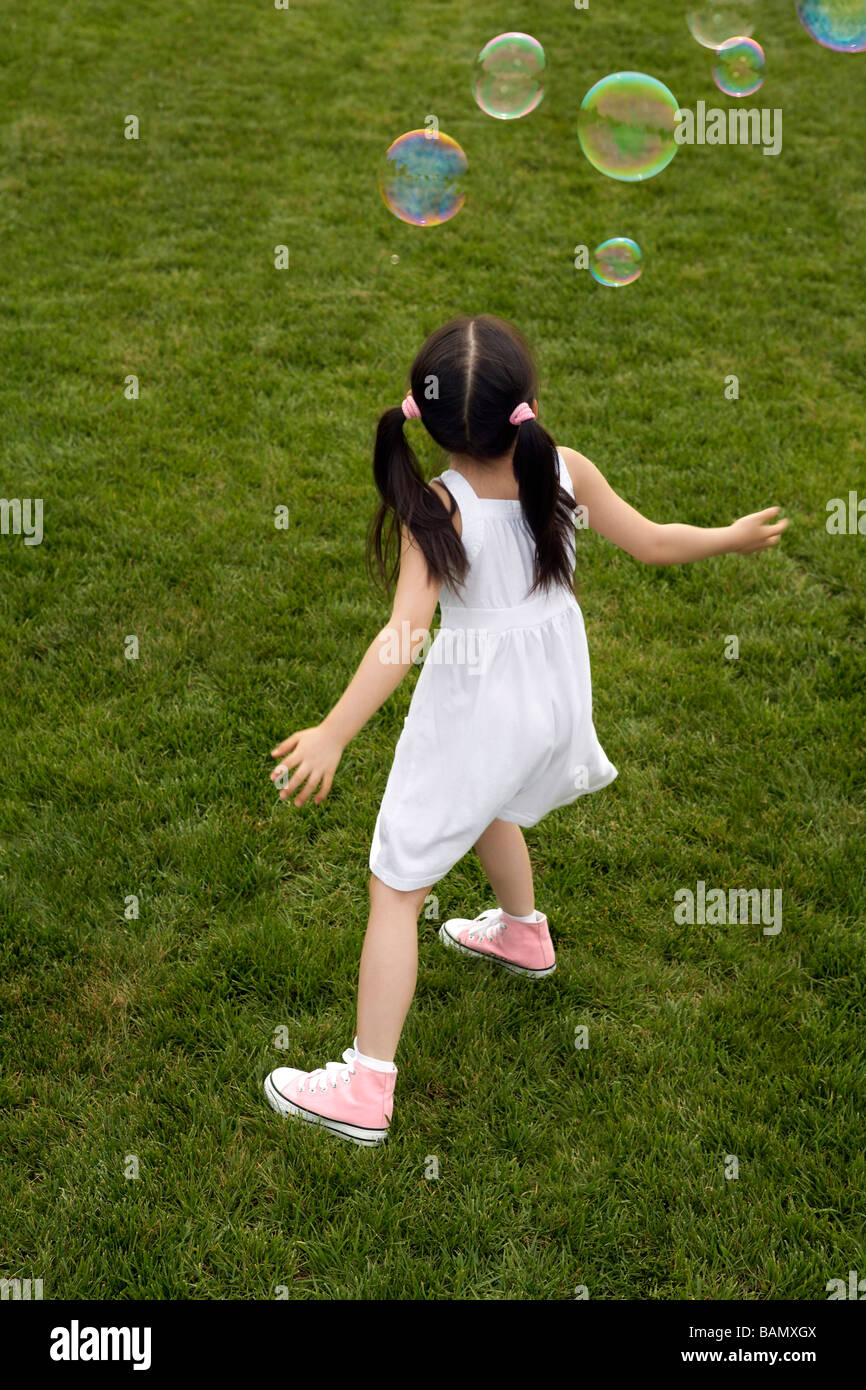Young Girl Chasing Bubbles In Park Stock Photo - Alamy