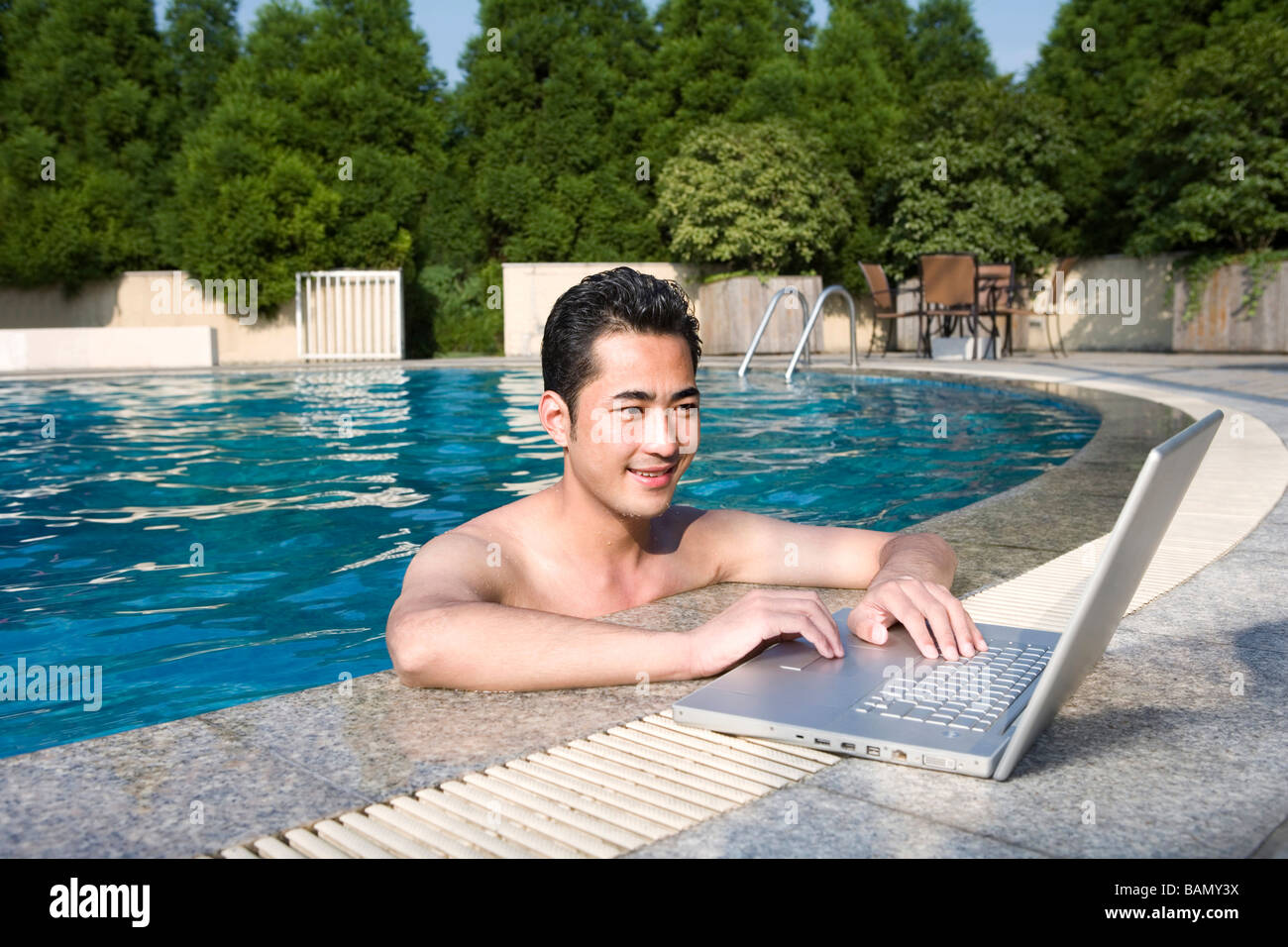 A man uses his laptop poolside Stock Photo - Alamy