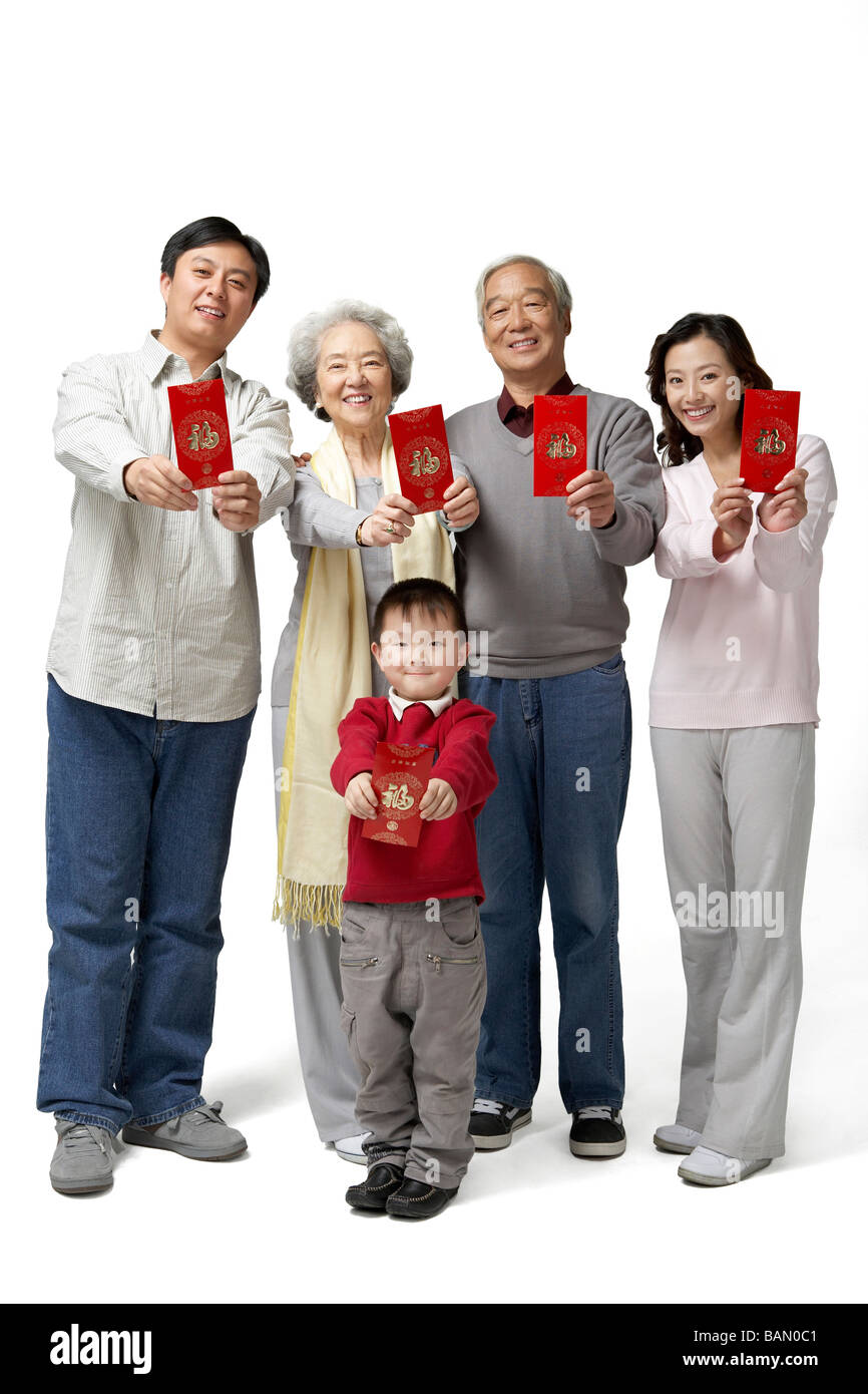 Portrait of a three generation family holding out red envelopes for ...