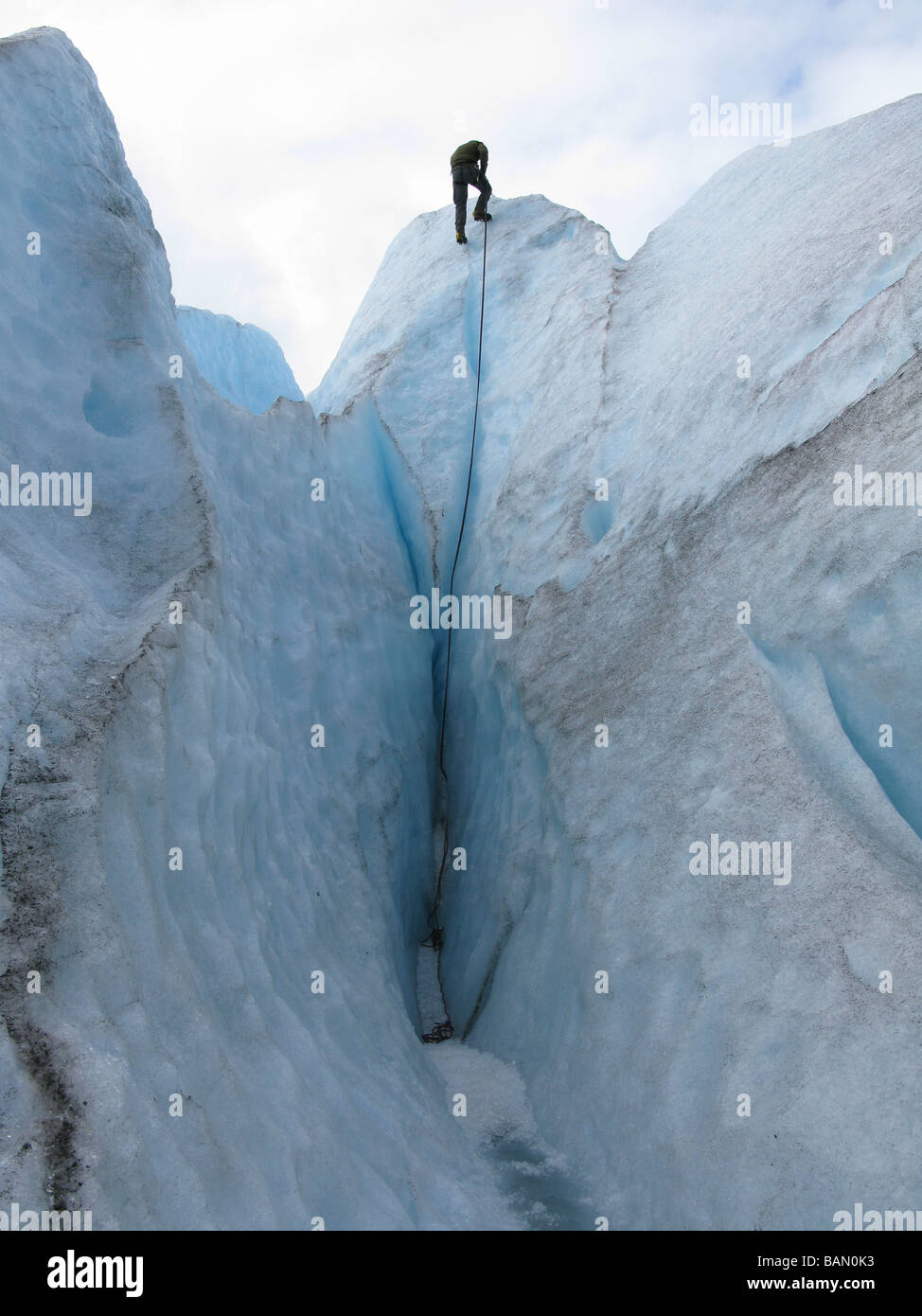 Ice climber reaches the top of a short crevasse in a glacier. Located ...