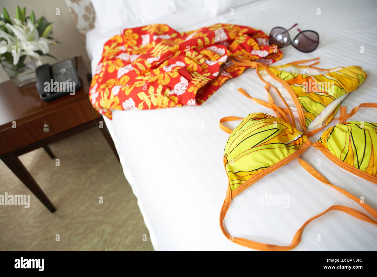 Bikini, swimming trunks and sunglasses on a bed Stock Photo - Alamy