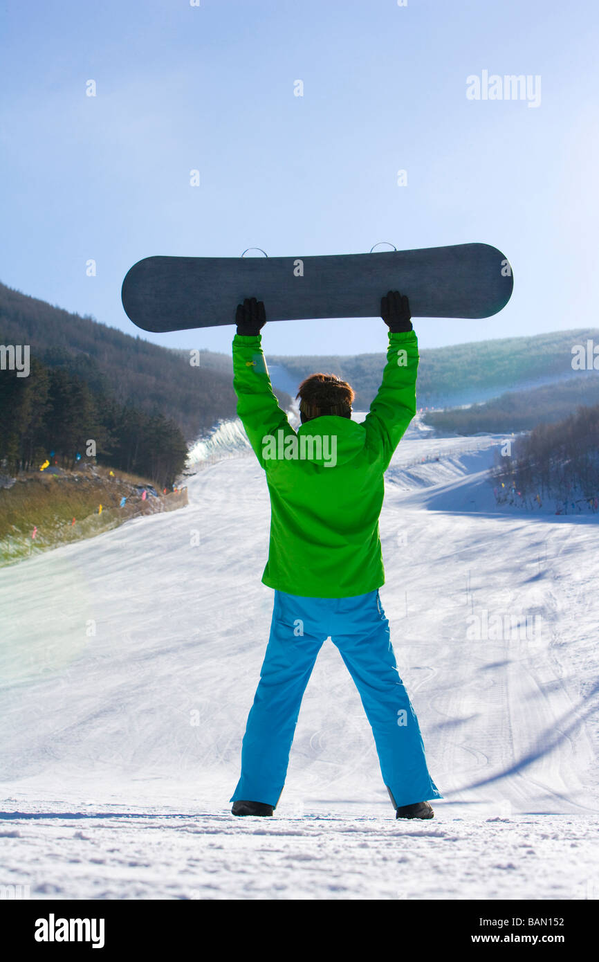 Rear view of a young man posing with his snowboard Stock Photo - Alamy