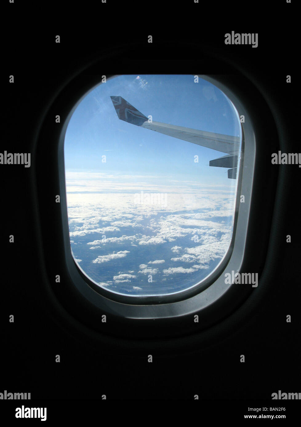 wing and sky at high altitude through the window of a passenger jet ...