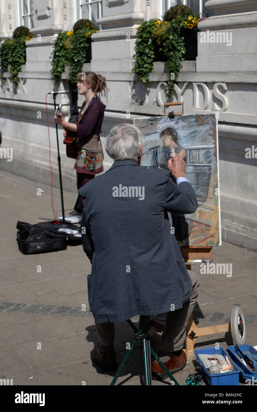 Street artist painting a picture of female busker Stock Photo - Alamy