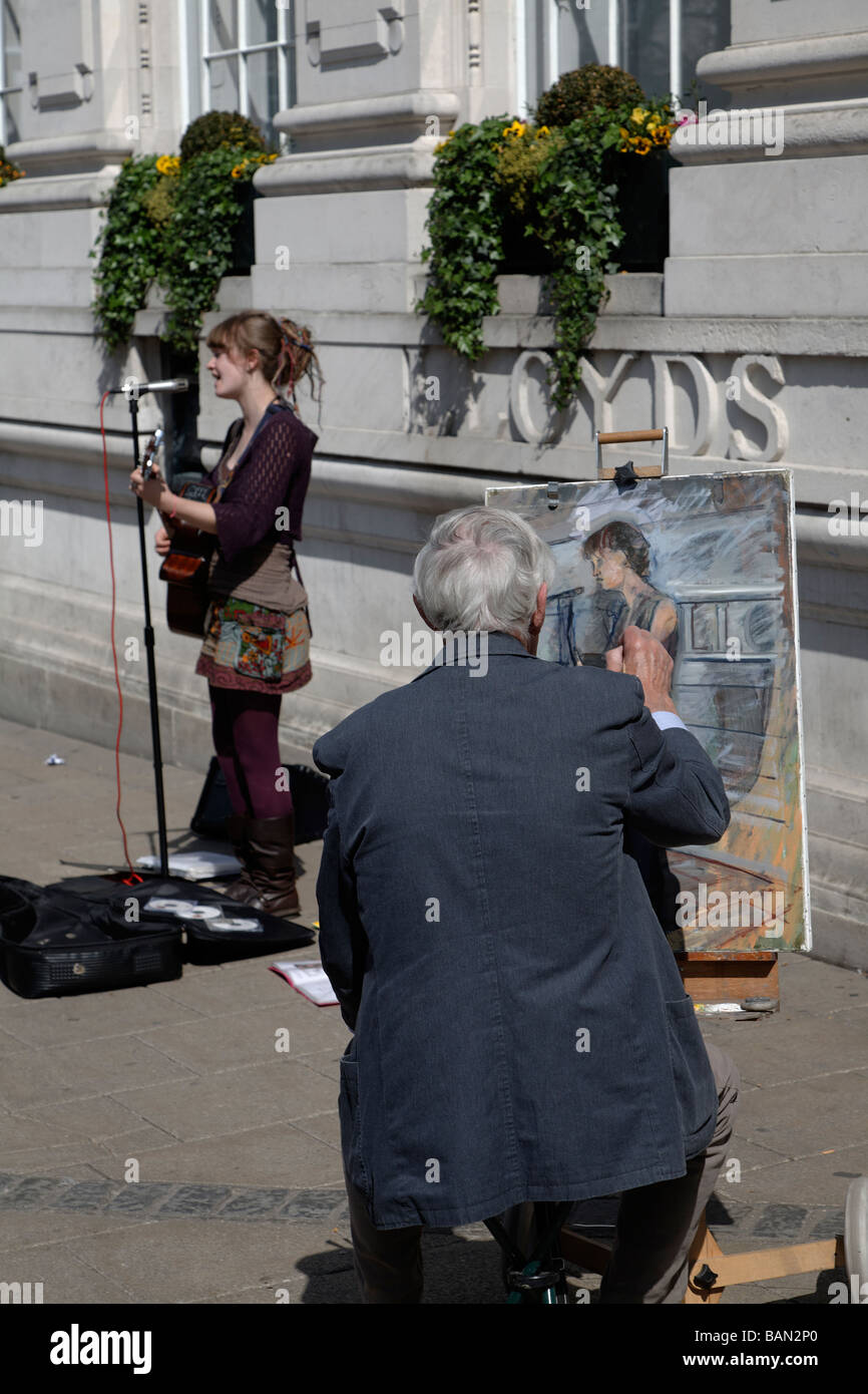 Street artist painting a picture of female busker Stock Photo - Alamy