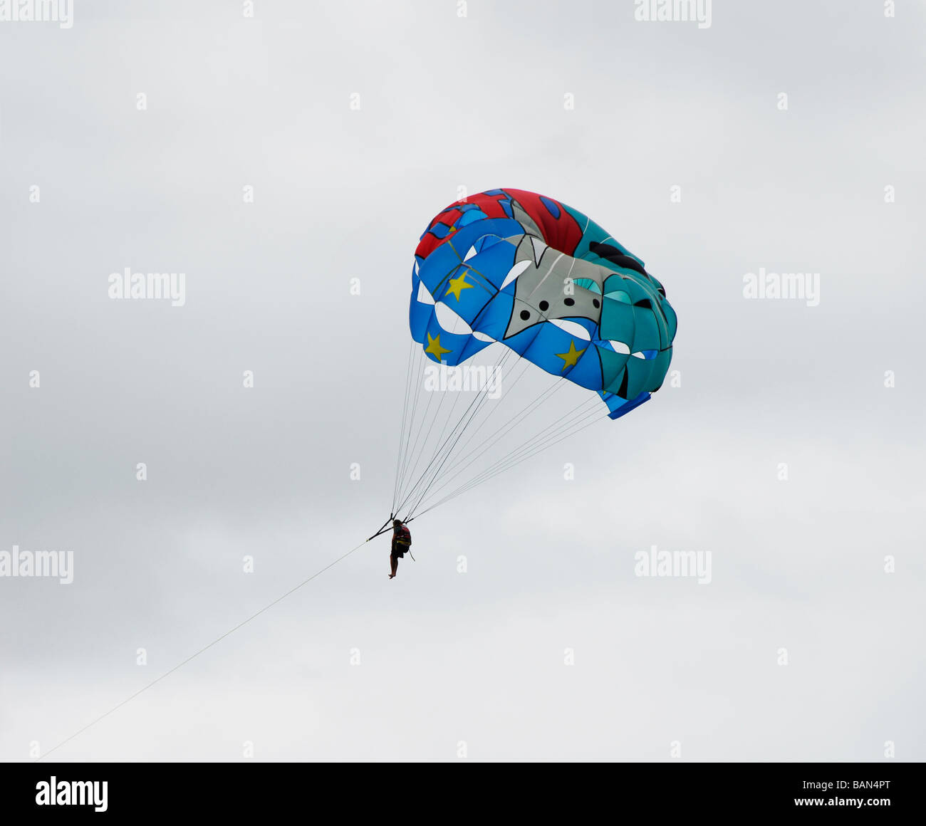 Person parasailing: hanging from parachute whilst being pulled by a ...