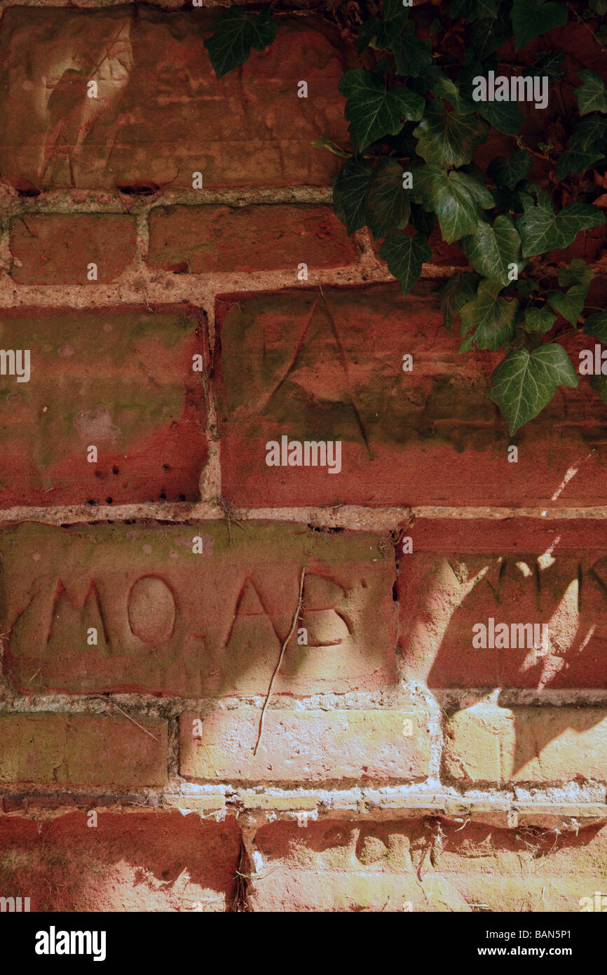 An old red sandstone wall with various letters scratched into the ...