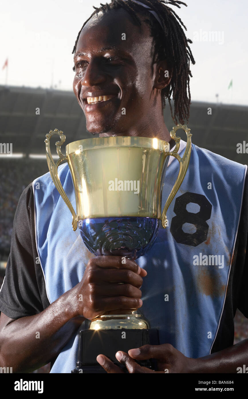Male soccer player proudly holding trophy Stock Photo - Alamy