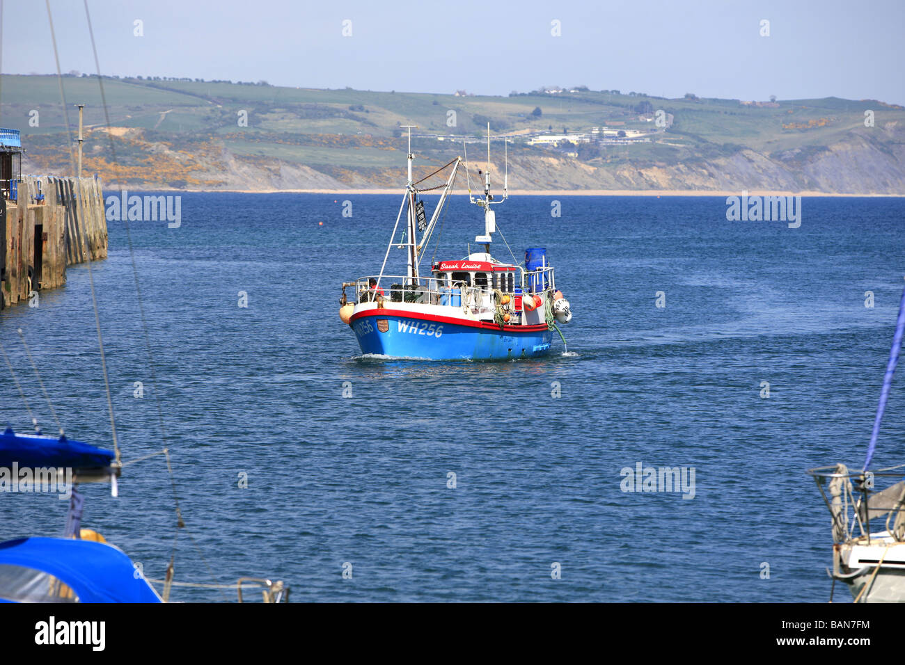 A small shell fish fishing boat slowly motors into Weymouth Harbour to ...