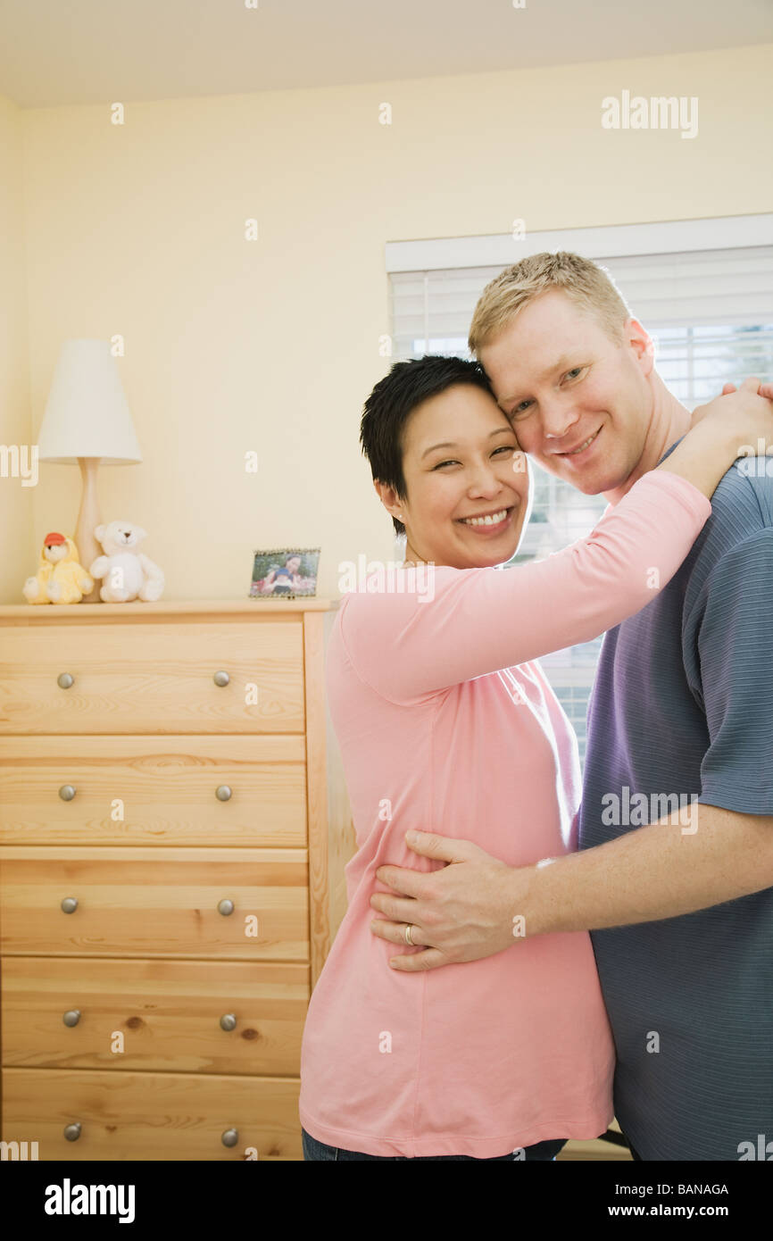 Pregnant couple hugging indoors Stock Photo - Alamy