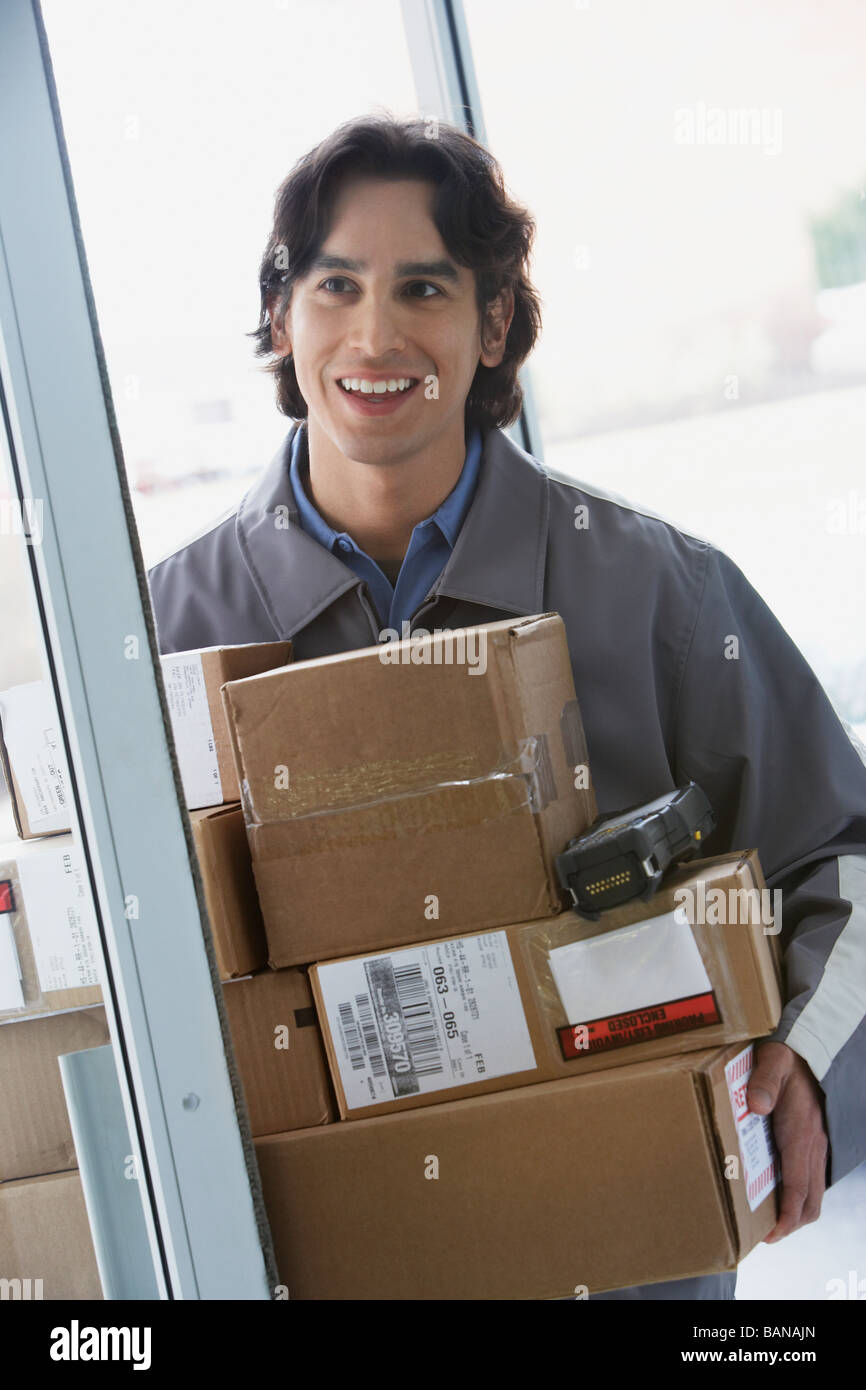 Male delivery person with stack of boxes Stock Photo - Alamy