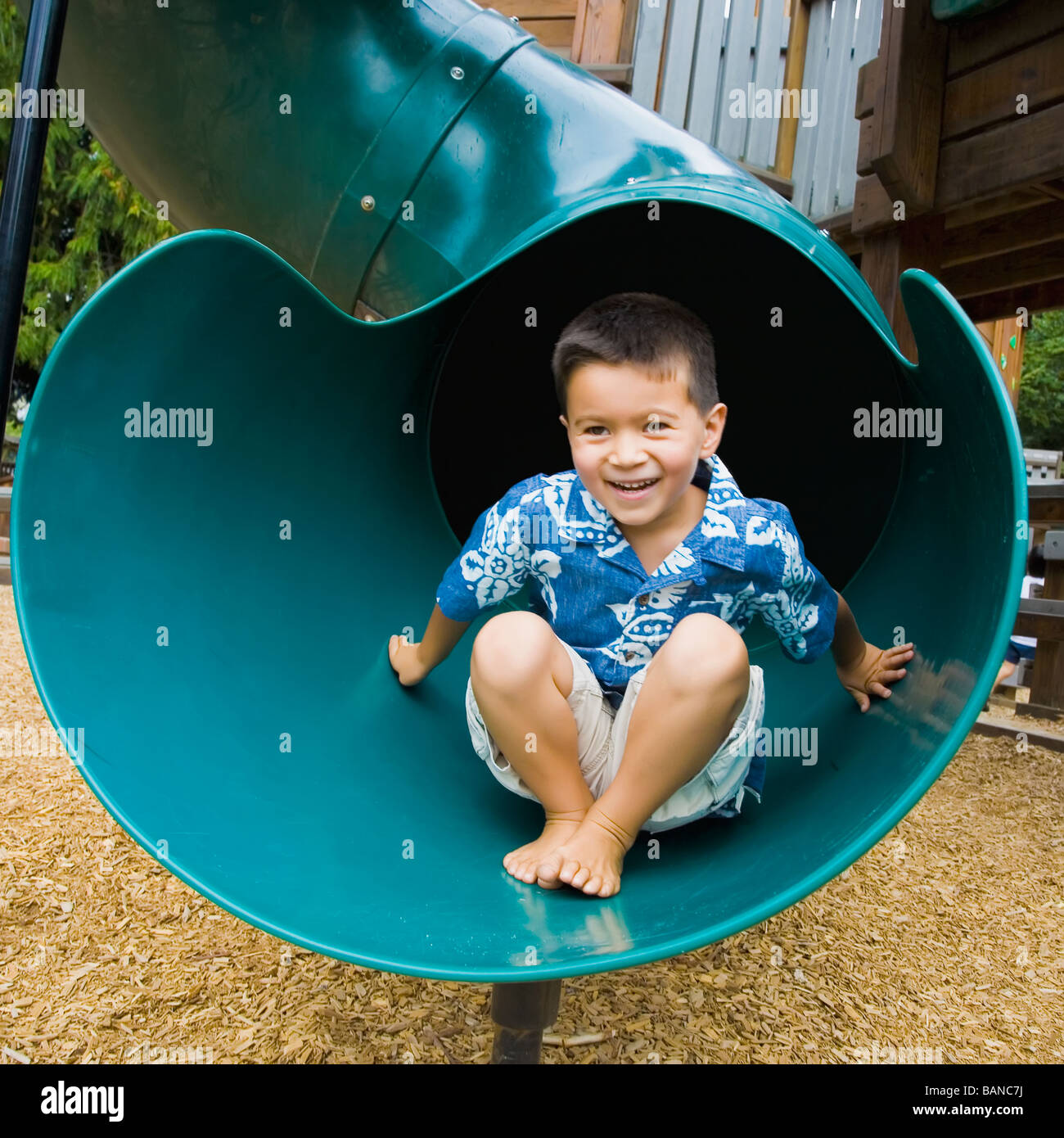 Mixed race boy sliding in playground Stock Photo - Alamy