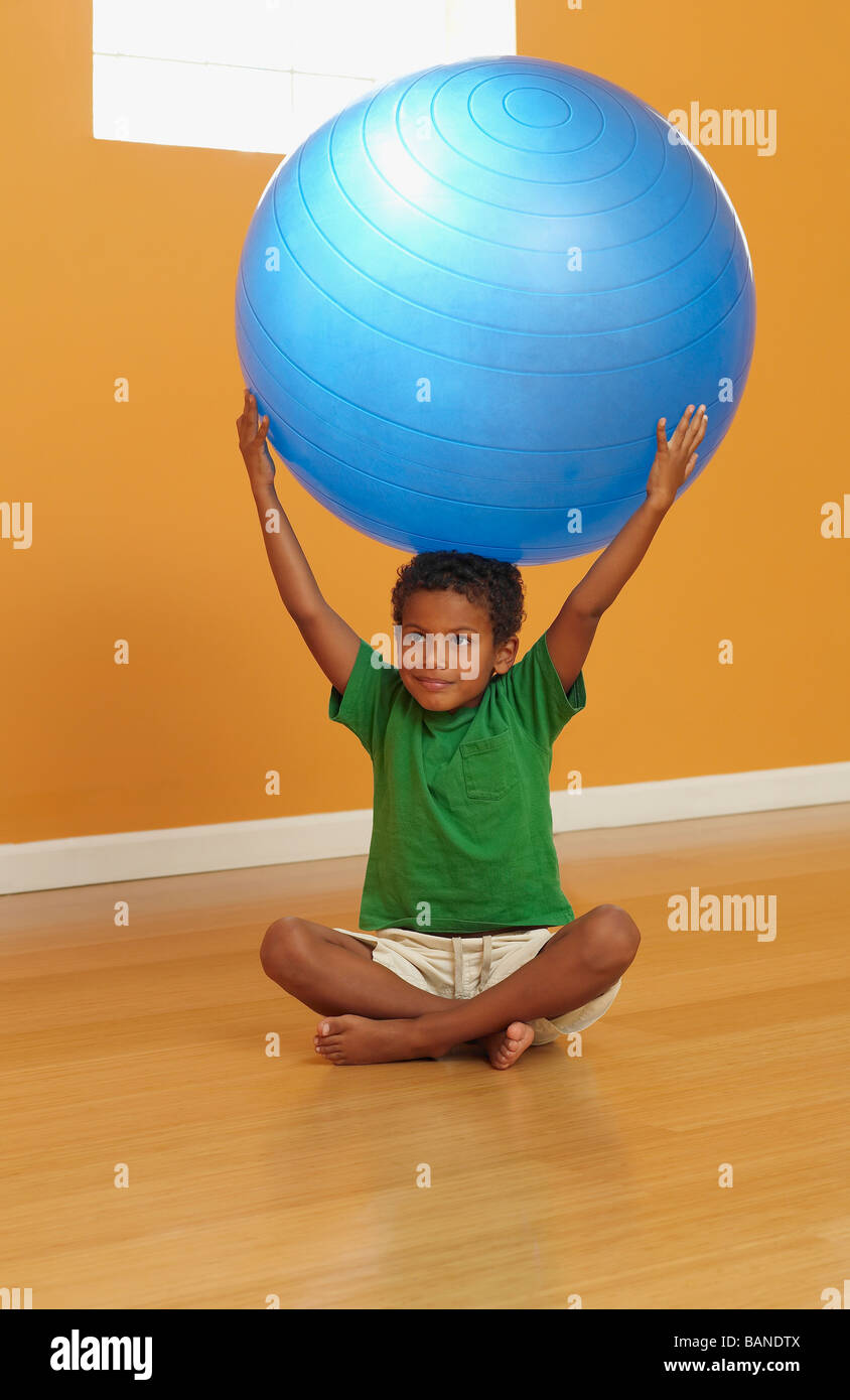 Mixed race boy lifting exercise ball Stock Photo - Alamy