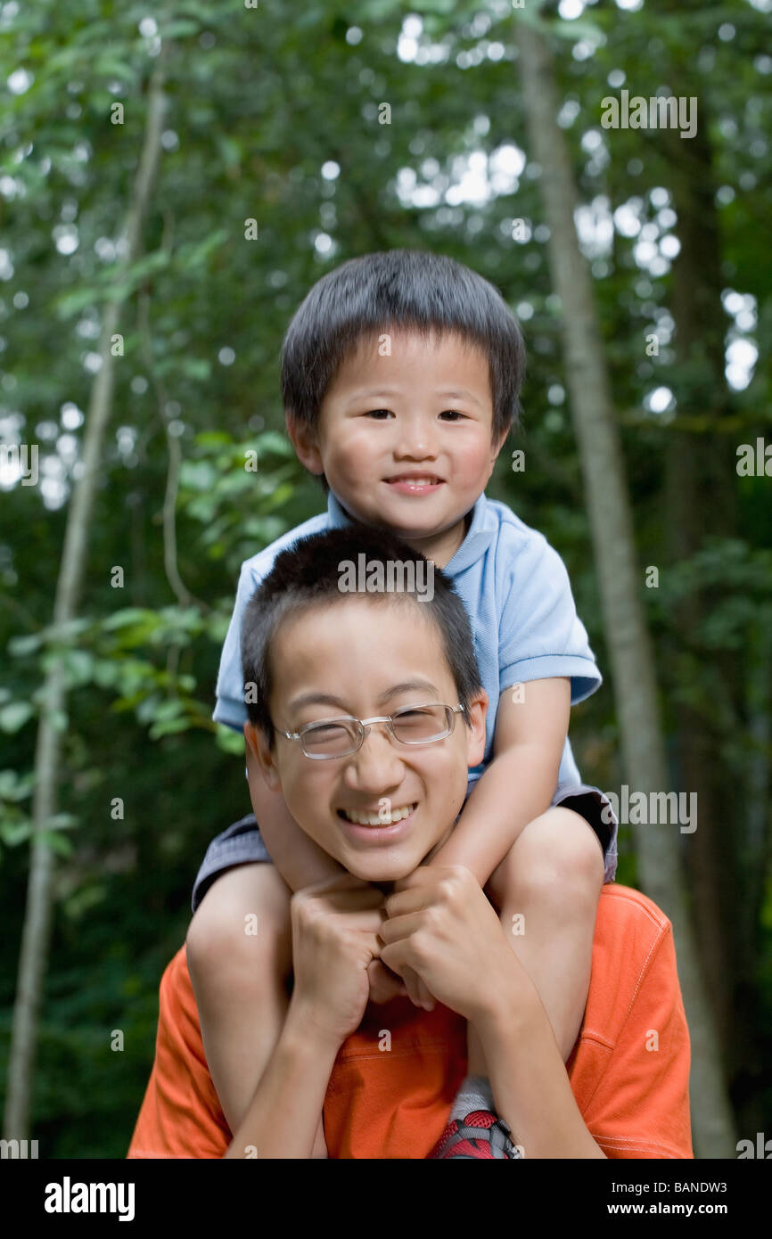 Asian boy carrying brother on shoulders Stock Photo - Alamy