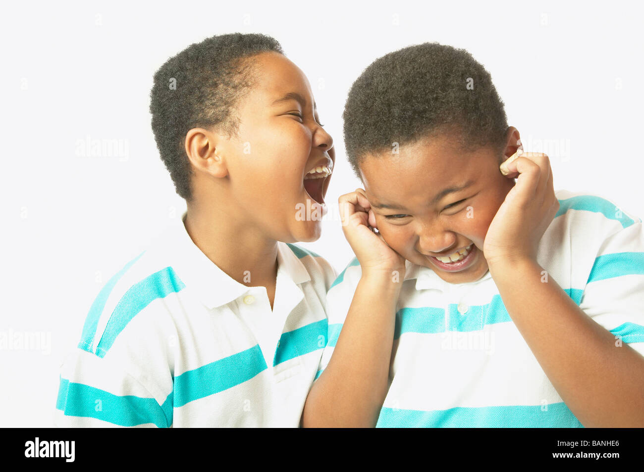 Young African boy yelling into twin brother's ear Stock Photo - Alamy