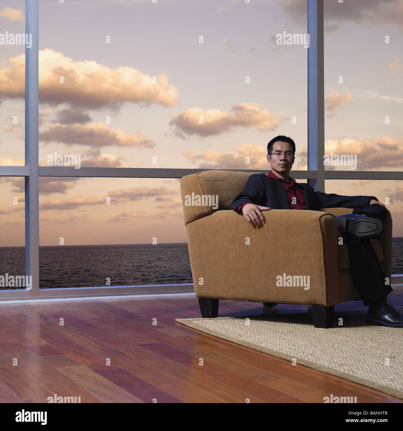 Asian man sitting next to window overlooking water Stock Photo - Alamy