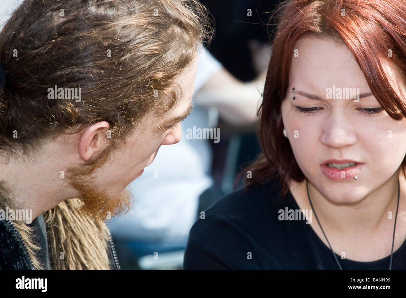 Young European couple sitting close together outside in the sunshine ...