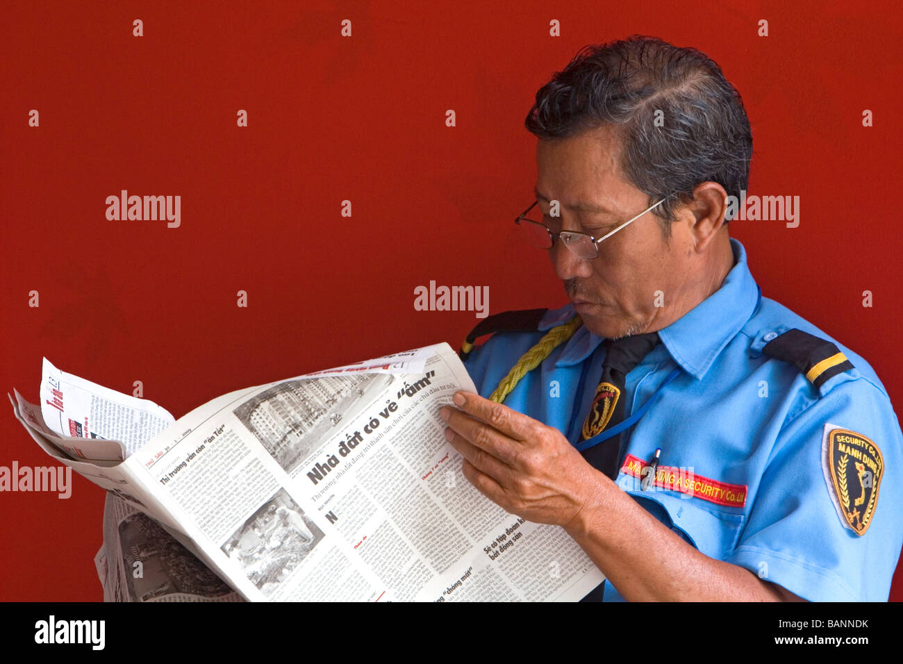 Vietnamese security guard reading a newspaper in Ho Chi Minh City ...