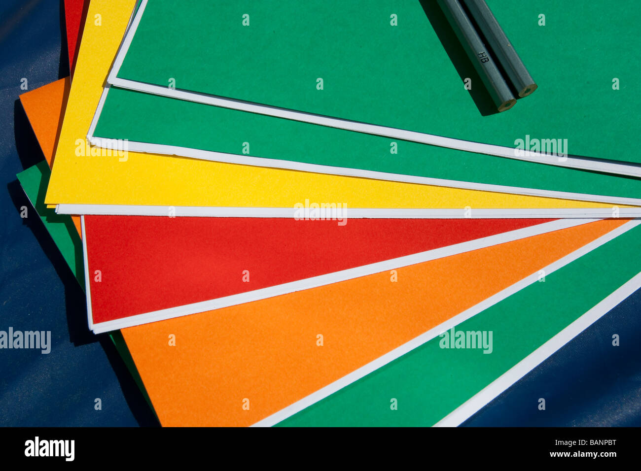 Brightly coloured school childrens exercise books and pencils on a ...