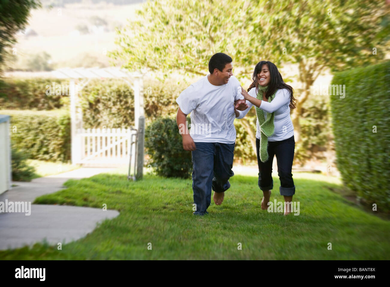 Hispanic brother and sister running on grass Stock Photo - Alamy