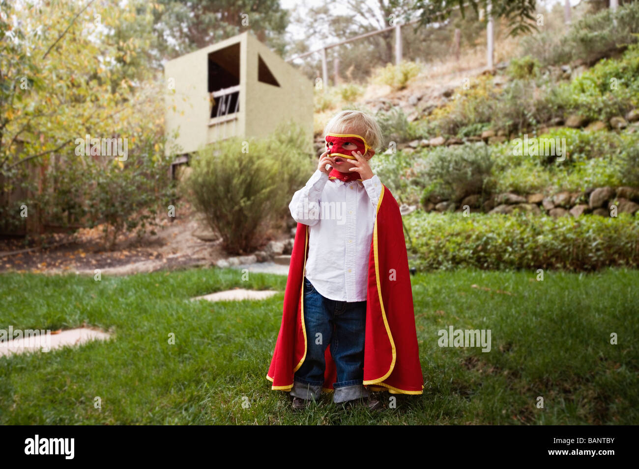 Boy wearing cape and mask in backyard Stock Photo - Alamy